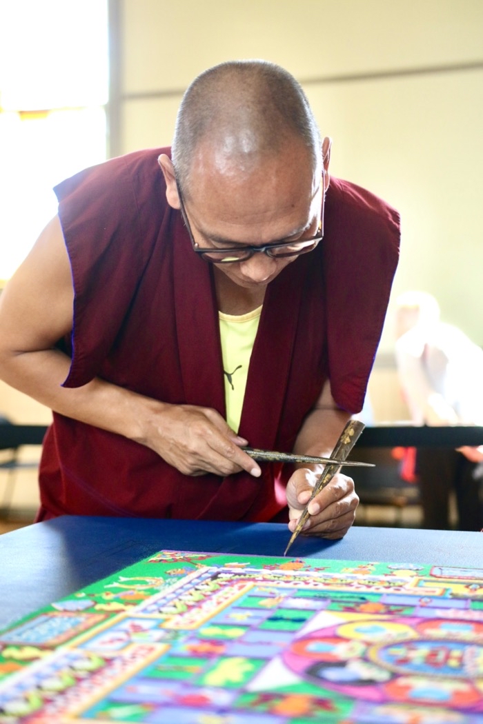 Geshe Lundup Phuntshok, a Buddhist monk, works on a sand mandala, or ...